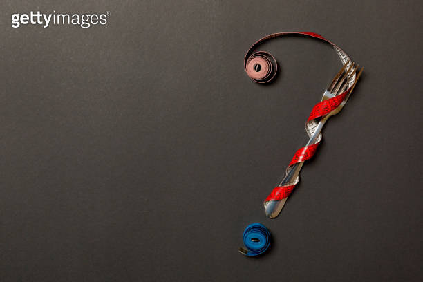 Top view of question mark made of fork and measuring tape on black ...