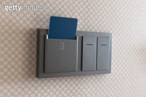 Electronic lock with card inserted and light switches on concrete wall ...