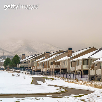 Square Facade of homes viewed against snow capped mountain and white ...