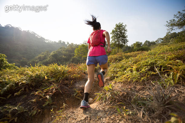 Woman trail runner running up on mountain slope in tropical forest 이미지 ...