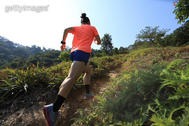 Woman ultramarathon runner running up on mountain slope in tropical ...