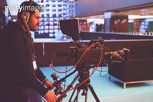Video camera operator working with his equipment at indoor event ...
