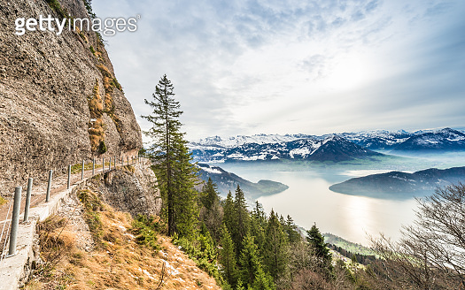 Tourist walking path along the cliff. Panorama of the Alps in ...