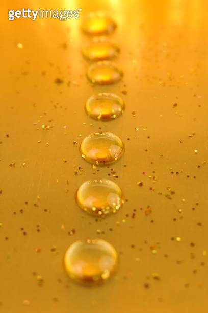 Golden drop row with gold glitter on golden blurred background.water ...