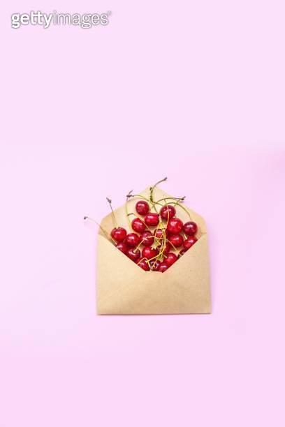 Envelope with ripe red cherry berries on a pink background. Invitation ...