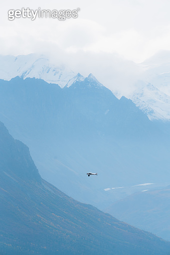 Plane flying through valley in remote mountains in Alaska 이미지 ...