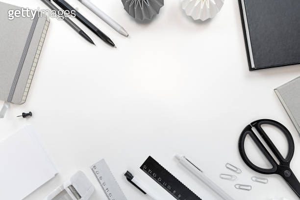 High angle flat lay desk with various black, gray and white stationery ...