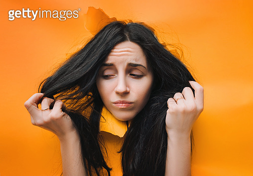 A young girl holds her problematic dry hair and expresses frustration ...