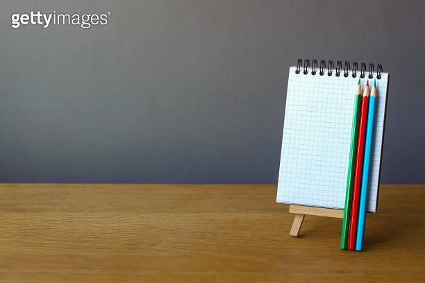 Back to school concept, open notebook on a miniature easel and three ...
