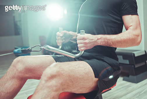 Man is training with equipment rowing training machine by pulling ...