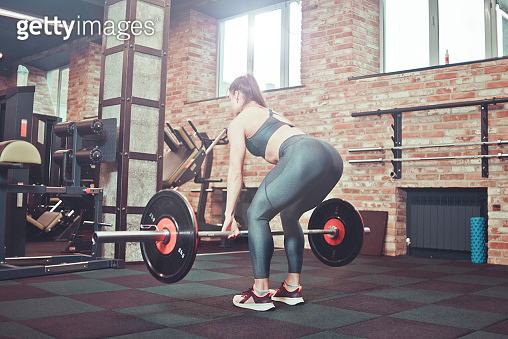 Muscular young fitness woman doing heavy deadlift exercise at gym Back ...