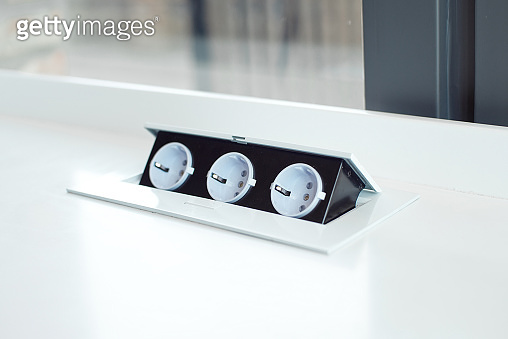 Pop-up internal socket in a white table, charging for phones and ...
