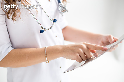female doctor holds folder with papers, dressed in white gown, cures ...
