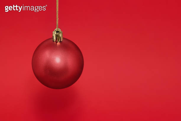 Red Christmas bauble hanging from gold string isolated against a red ...