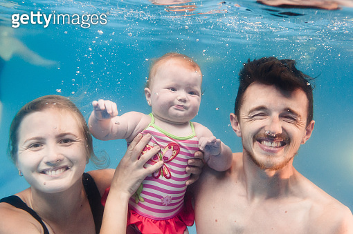 Mother, father with daughter learn to swim on swimming lesson, doing ...