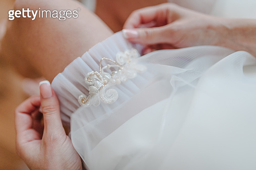 Woman wearing a garter on the leg. The bride holds in hand Ñ lose-up ...