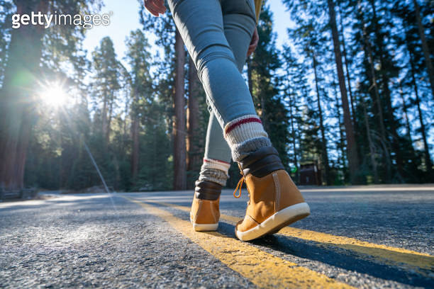 Low angle view of woman walking on middle lane highway in USA 이미지 ...
