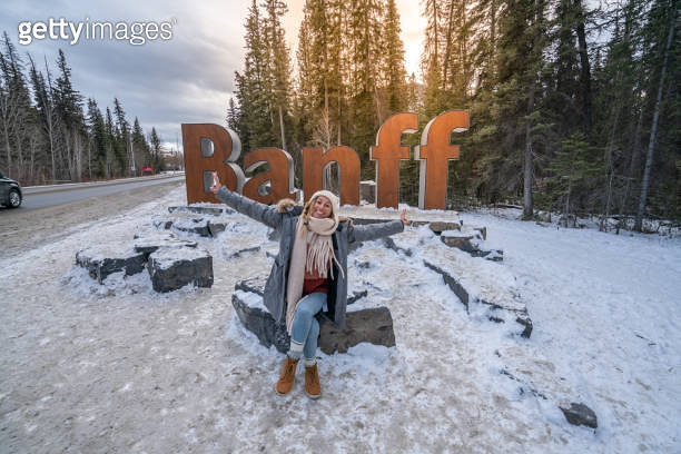 Young woman posing in front of Welcome to Banff sign in Banff town ...