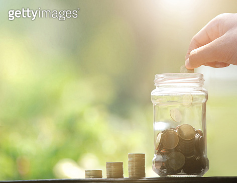 Man hand dropping coin and coins and jar. 이미지 (1159189174) - 게티이미지뱅크