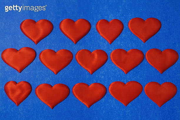 Top view of many red hearts in row on blue cardboard background ...