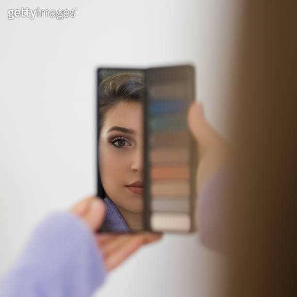 Reflection in a mirror of young woman apply makeup brush for eyes 이미지 ...