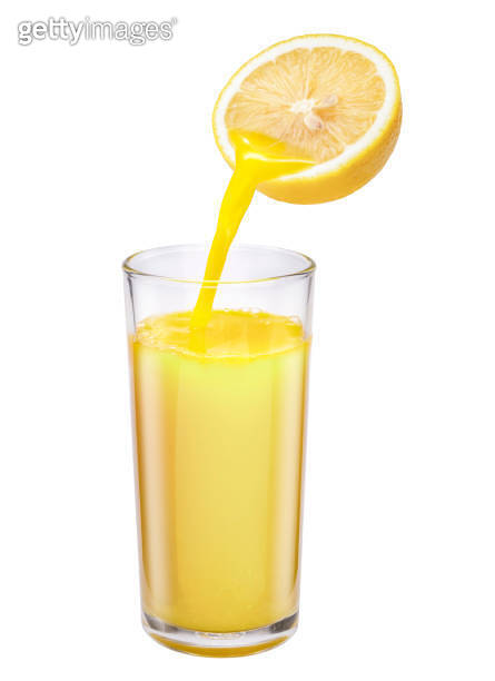 Fresh lemon juice pours into the lemon juice glass isolated on white ...