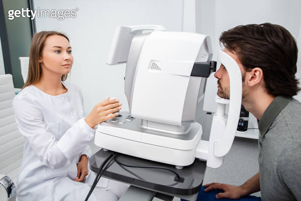 Eye doctor woman is doing a diagnostic vision exam adult man. Concept ...