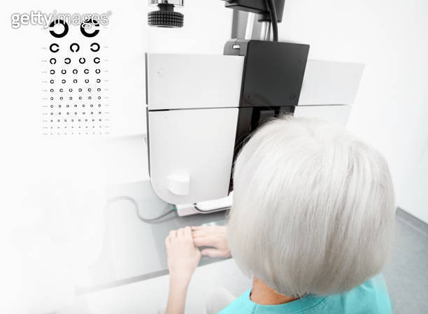 Checking elderly woman's eyesight on the modern phoropter. Procedure ...