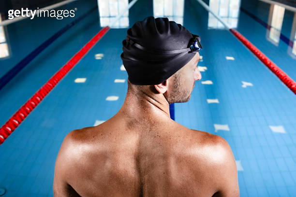 Swimmer wearing a swimming cap, standing near pool, get ready start ...