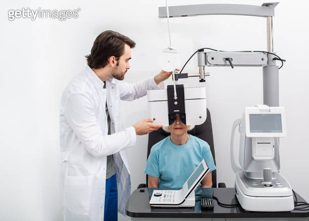 Serious experienced optometrist doing site testing for a patient using ...