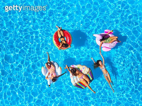 Aerial of hot pretty girls in bikini swimming in pool on floaties. Top ...