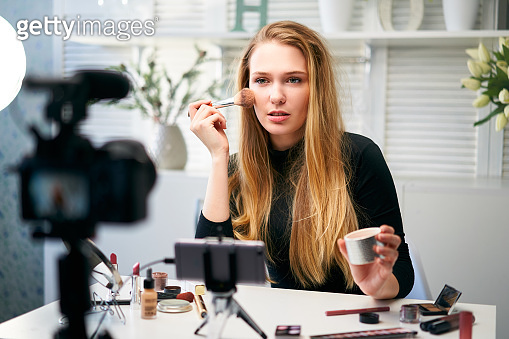 Beauty blogger woman filming daily make-up routine tutorial at camera ...