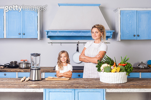 Happy beautiful mother in apron and little daughter standing with ...