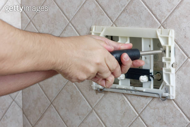 Repairman hands unscrewing a screw flush toilet box to fix bathroom ...
