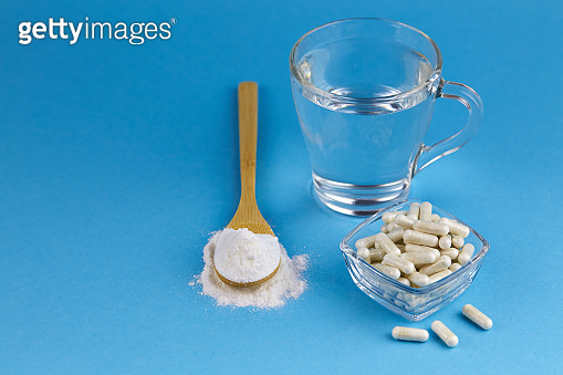 Collagen protein powder in spoon and collagen capsules in jar, a cup of ...