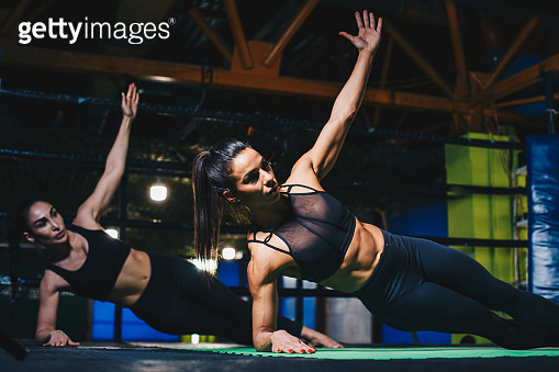 Beautiful woman training at the gym in a group class and doing side ...