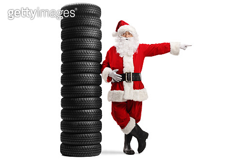 Full length portrait of santa claus leaning on a pile of tires and ...