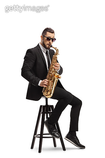 Elegant musician in a black suit playing a saxophone and sitting on a ...