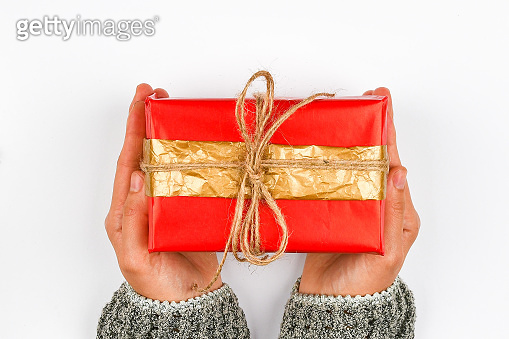 Red and gold gift wrap in the hands. Knitted with a bow on a white ...