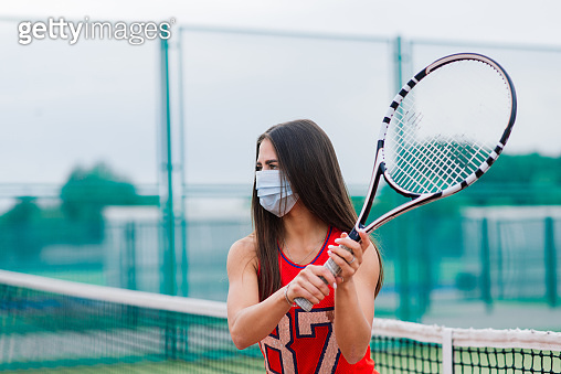 Portrait of tennis player girl holding racket outside with protective ...