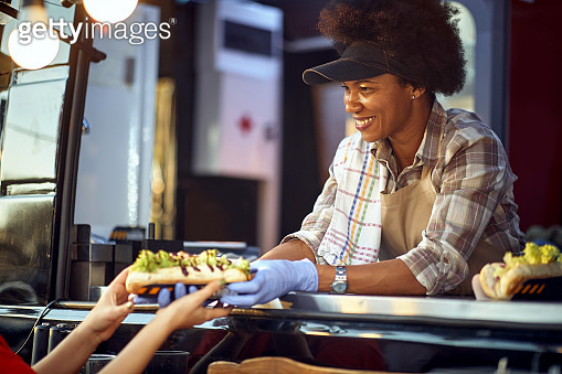 afro-american female employee in fast food service giving sandwiches to ...