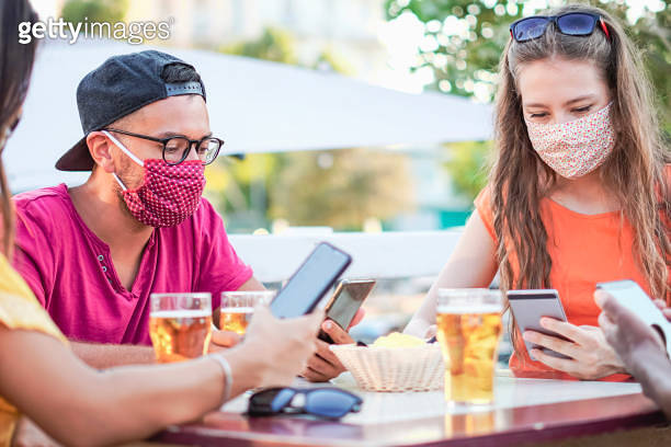 Friends using their smartphones in covid 19 times protected with face ...
