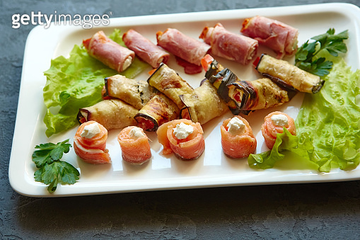 A dish with mini-canapes of salmon, eggplant and ham rolls with ...