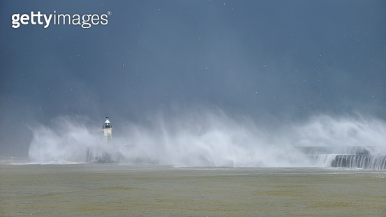 Massive waves crash over harbour wall onto lighthouse during huge storm ...