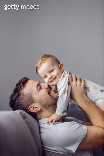 Young attractive caring father holding his beloved little son, singing ...