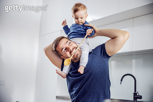 Young handsome single dad holding his only son on his shoulder, looking ...