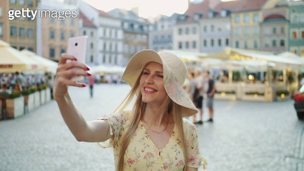 Young woman taking selfie on square. Attractive woman posing for selfie ...