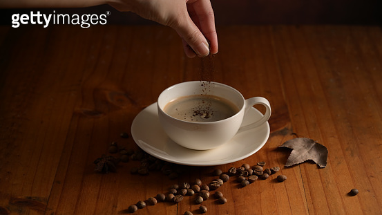 Close up view of barista hand adding coffee powder into cup on wooden ...