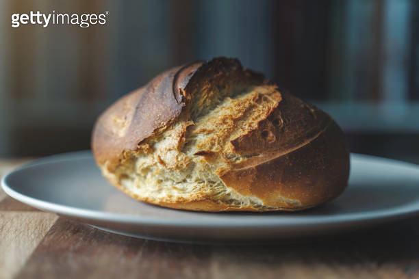 Fresh baked crusty loaf of homemade bread on the plate - Side view of ...