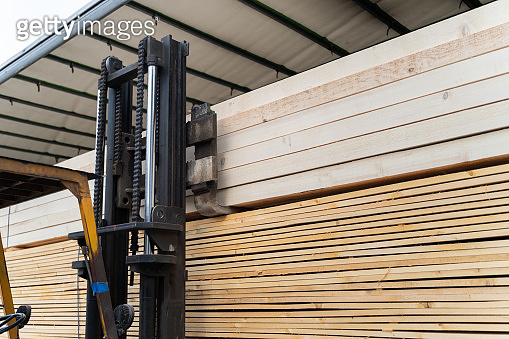 Close up on fork lifter loading or unloading timber wood and planks ...